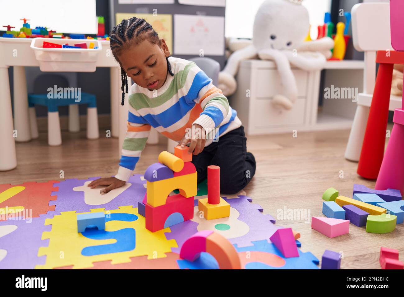 African american boy playing with construction blocks sitting on floor at kindergarten Stock ...