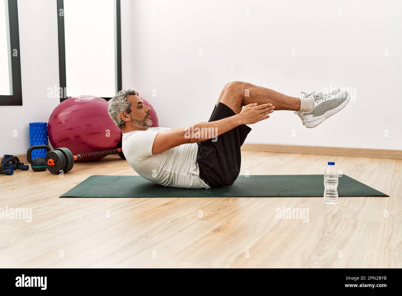 Middle age grey-haired man training abs exercise at sport center Stock ...