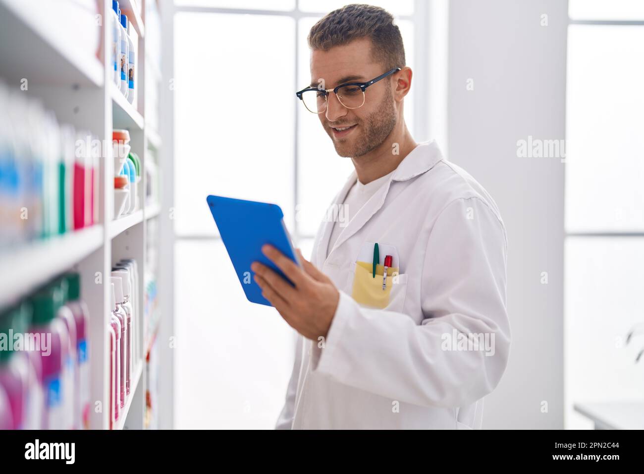 Young caucasian man pharmacist using touchpad working at pharmacy Stock ...