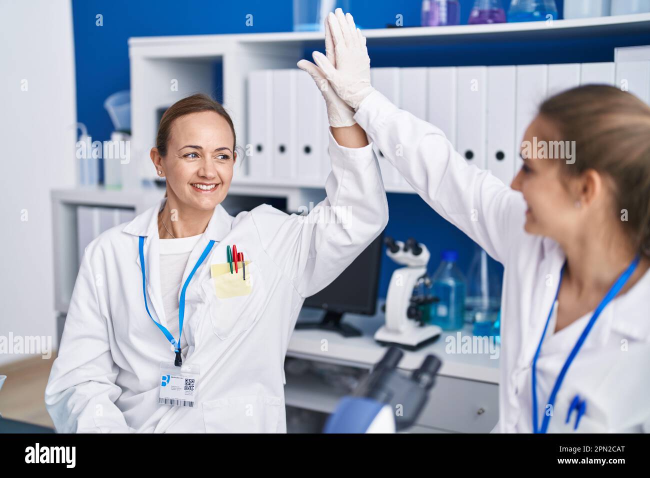 Two women scientists high five with hands raised up at laboratory Stock ...