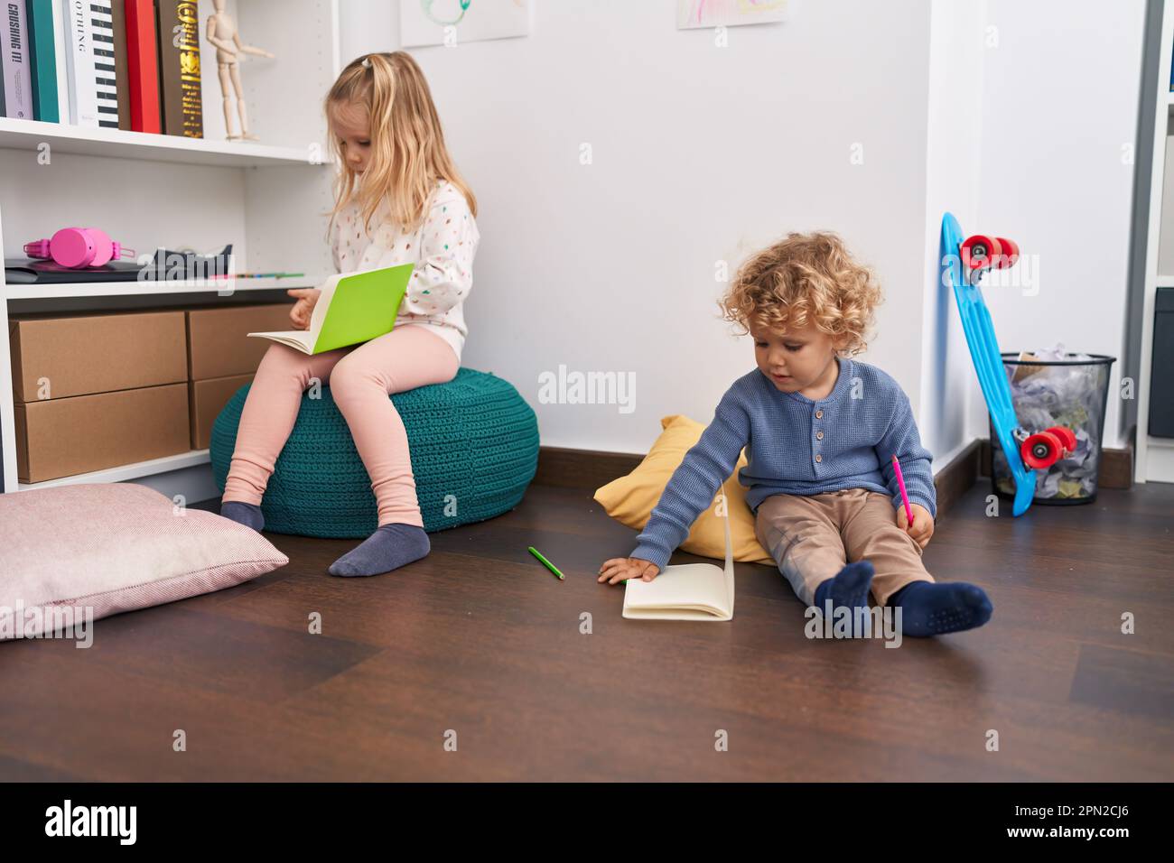 Adorable boy and girl students sitting on floor drawing on notebook at ...