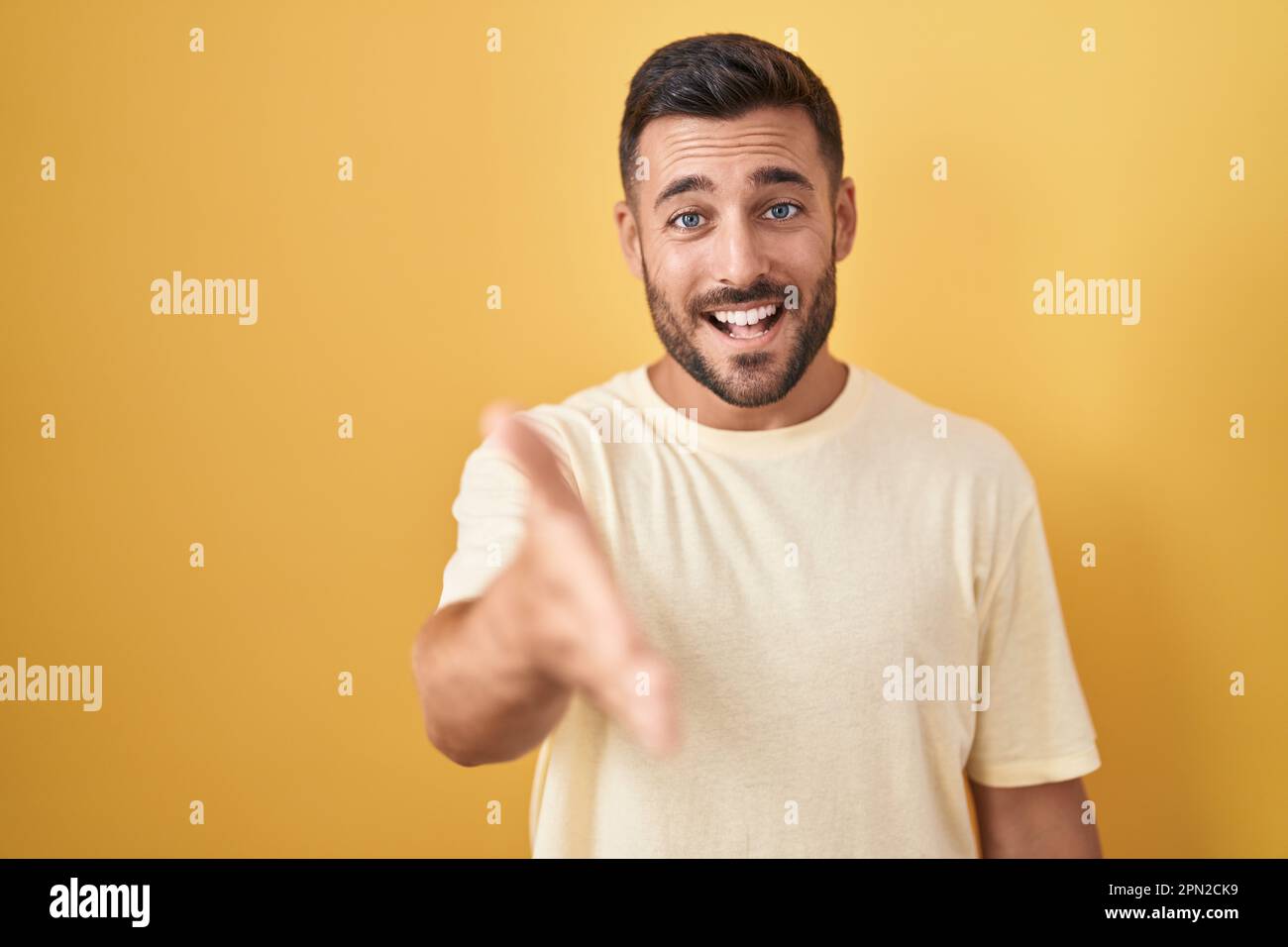 Handsome hispanic man standing over yellow background smiling friendly ...