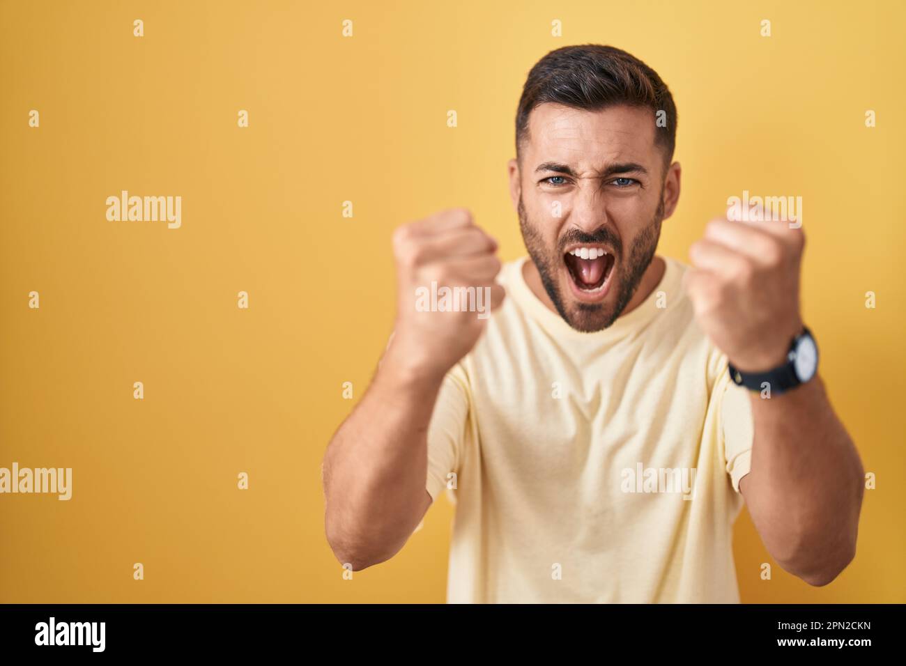 Handsome hispanic man standing over yellow background angry and mad ...