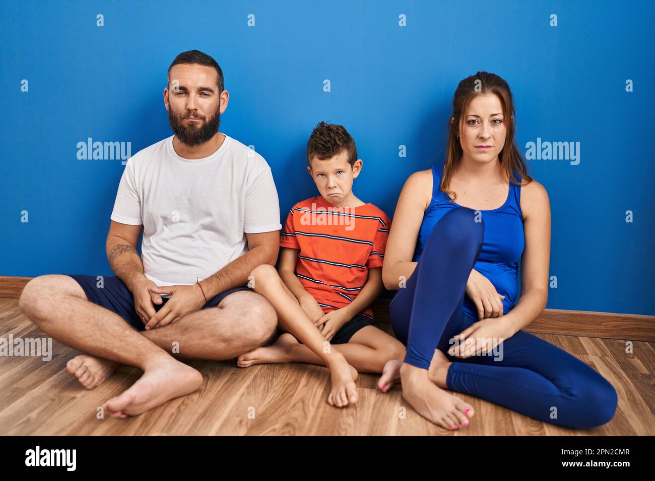 Family of three sitting on the floor at home depressed and worry for ...