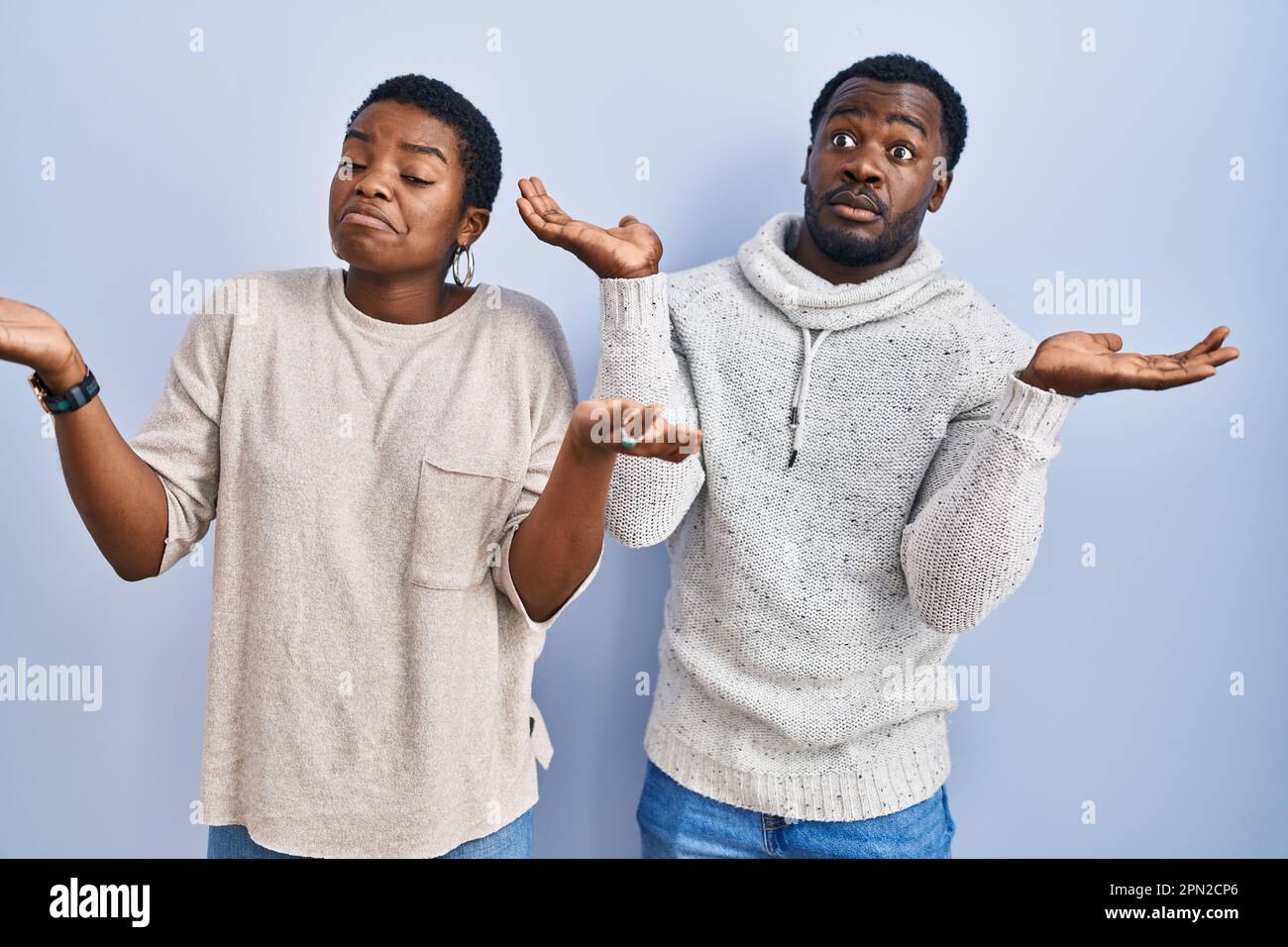 Young african american couple standing over blue background together ...