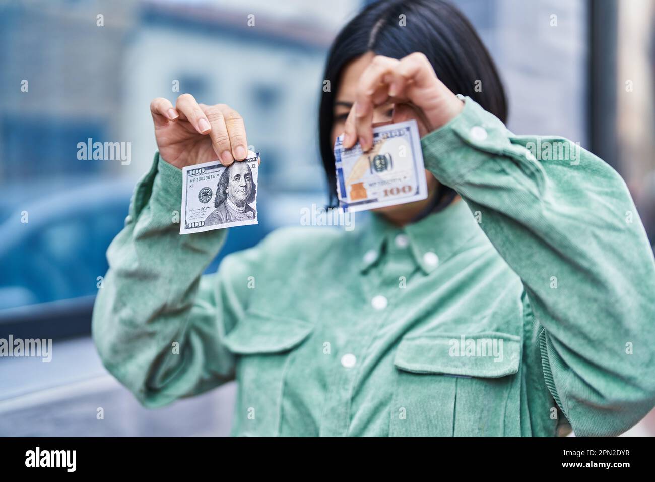 Young chinese woman breaking 100 dollars banknote at street Stock Photo ...