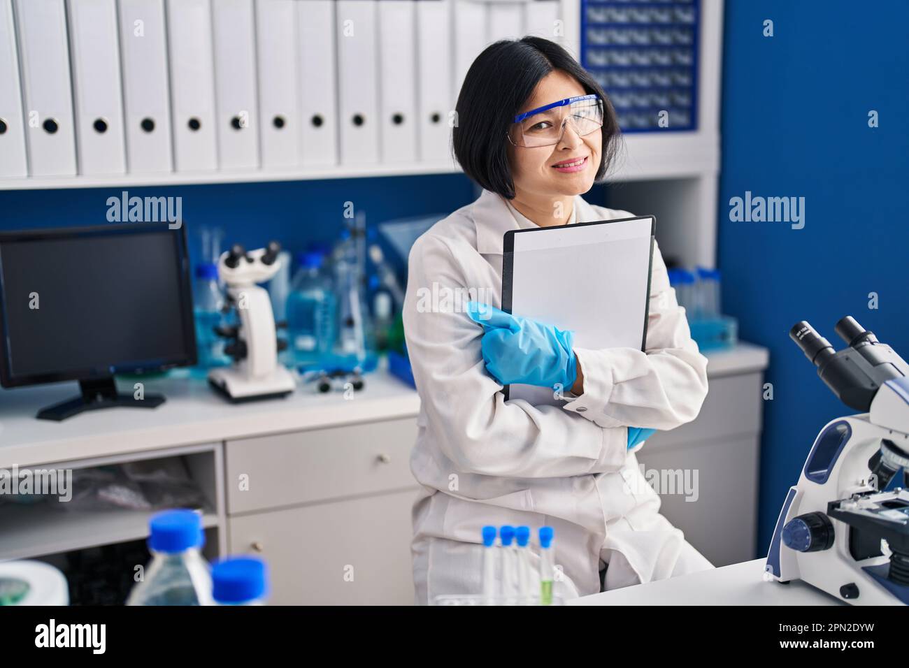 Young chinese woman scientist holding clipboard at laboratory Stock ...