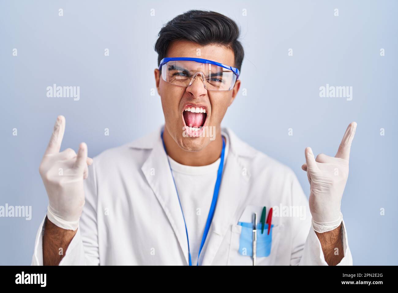 Hispanic man working as scientist shouting with crazy expression doing ...