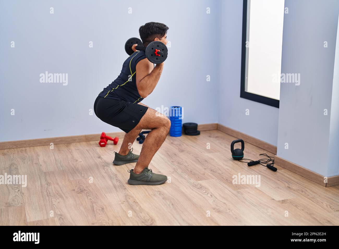 Young hispanic man smiling confident using bar with disc training at ...