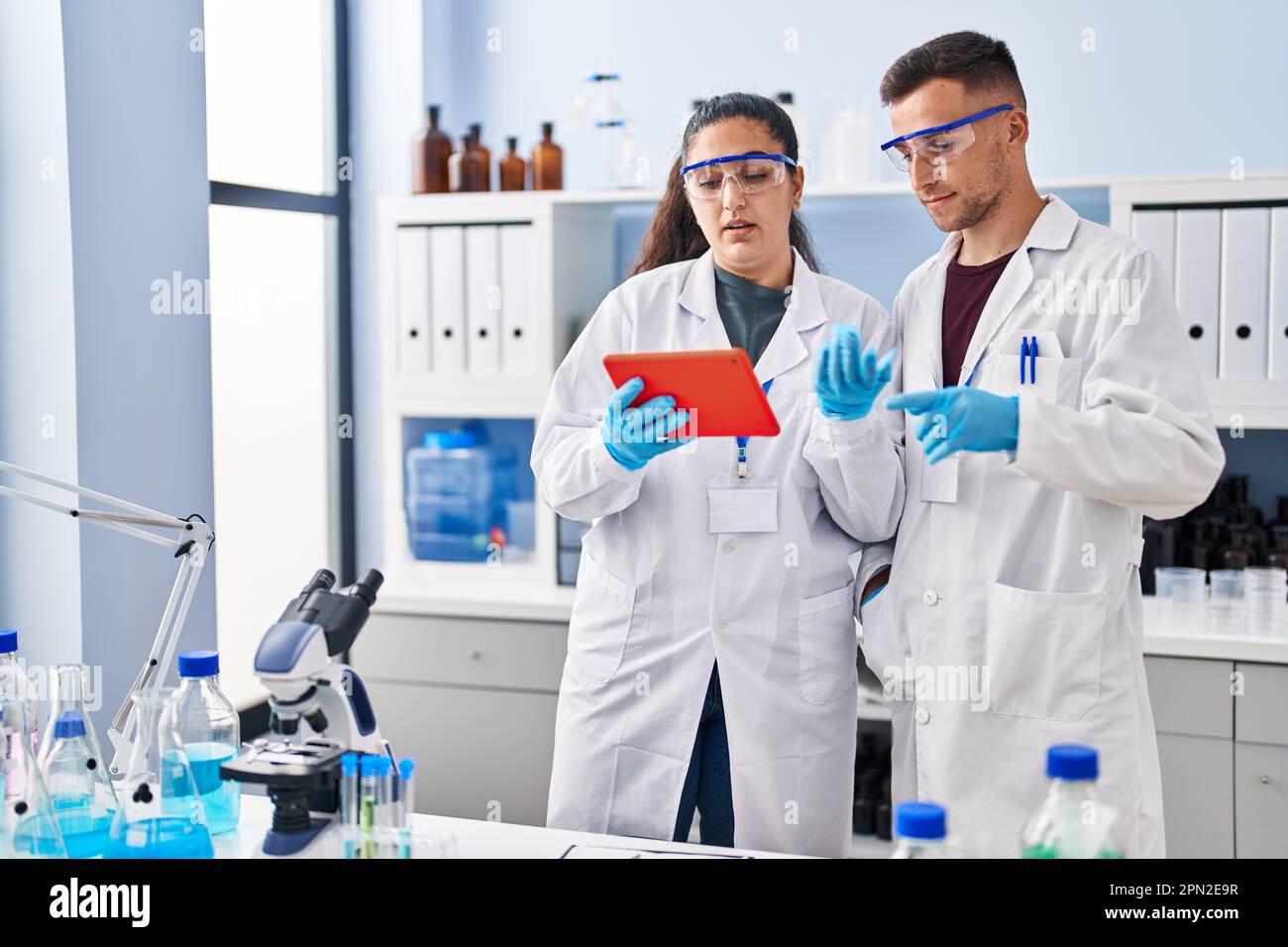 Man and woman wearing scientist uniform using touchpad at laboratory Stock Photo - Alamy