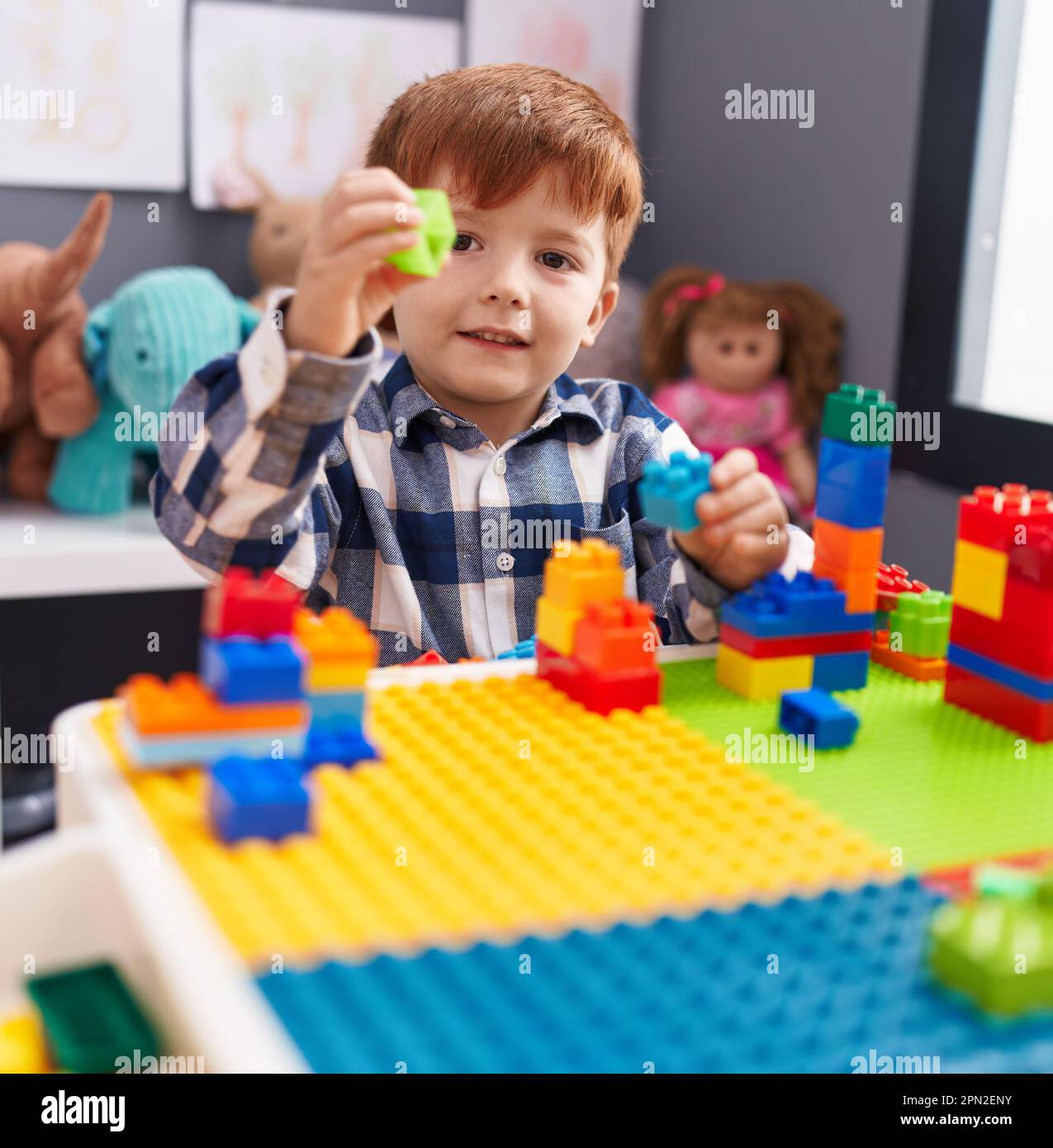Adorable toddler playing with construction blocks sitting on table at ...