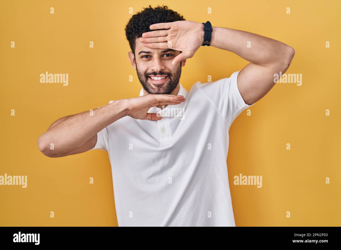 Arab man standing over yellow background smiling cheerful playing peek ...