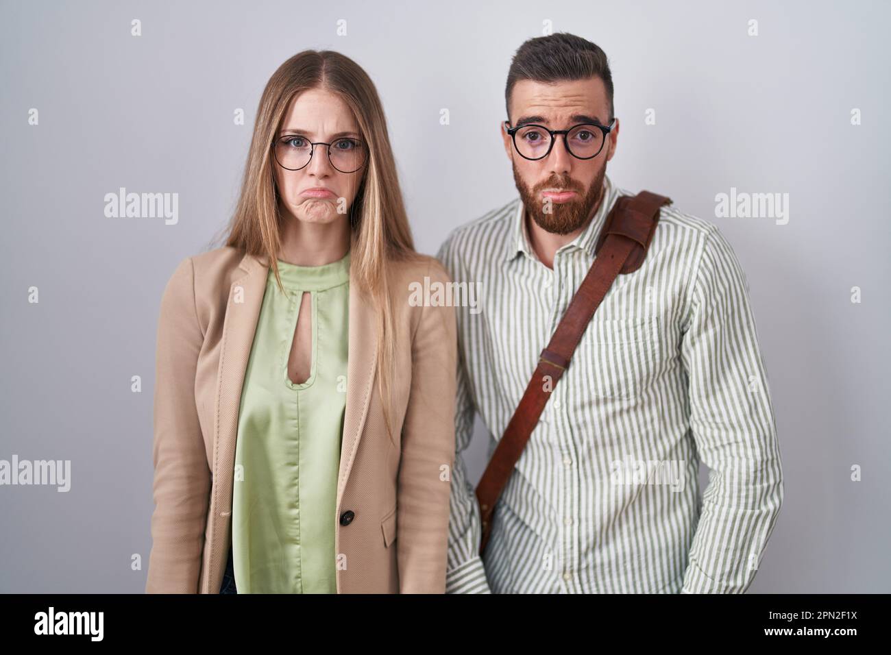 Young couple standing over white background depressed and worry for ...