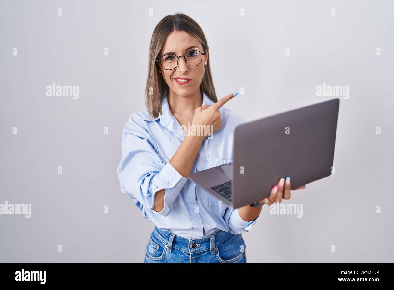 Young woman working using computer laptop pointing aside worried and ...
