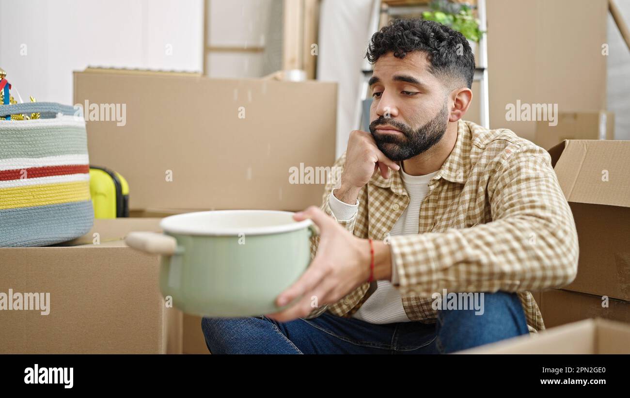 Young hispanic man holding cooking pot for water leak at new home Stock ...