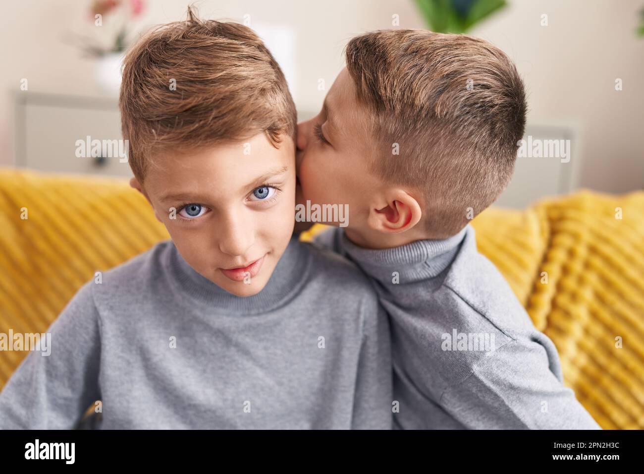 Adorable boys sitting on sofa kissing at home Stock Photo - Alamy