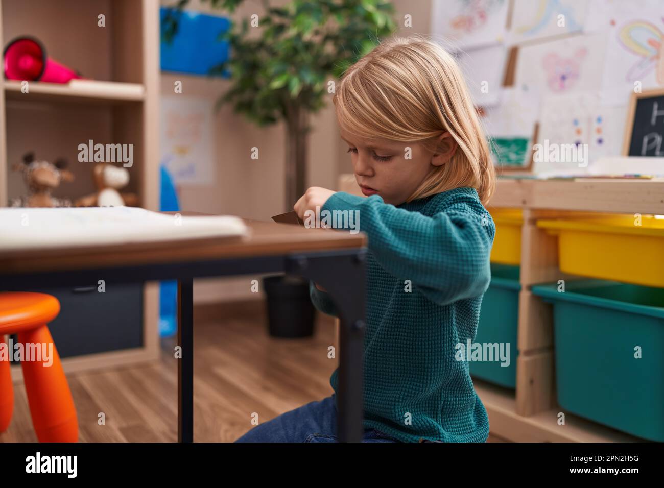 Adorable caucasian boy student cutting paper at kindergarten Stock ...