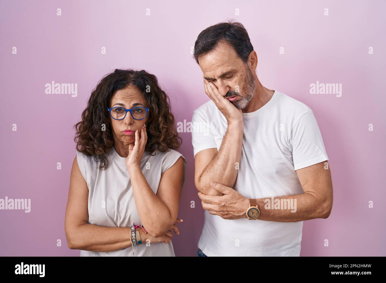 Middle age hispanic couple together over pink background thinking ...