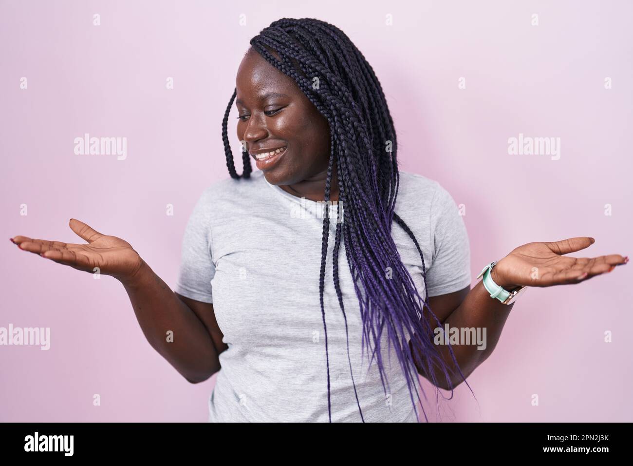 Young african woman standing over pink background smiling showing both ...
