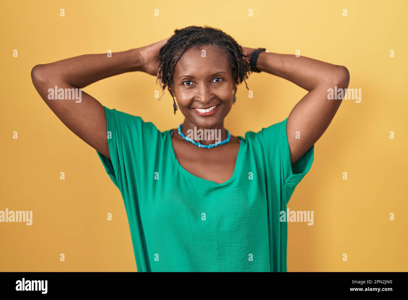 African woman with dreadlocks standing over yellow background relaxing ...