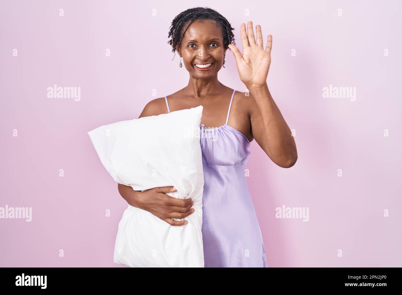 African Woman With Dreadlocks Wearing Pajama Hugging Pillow Waiving