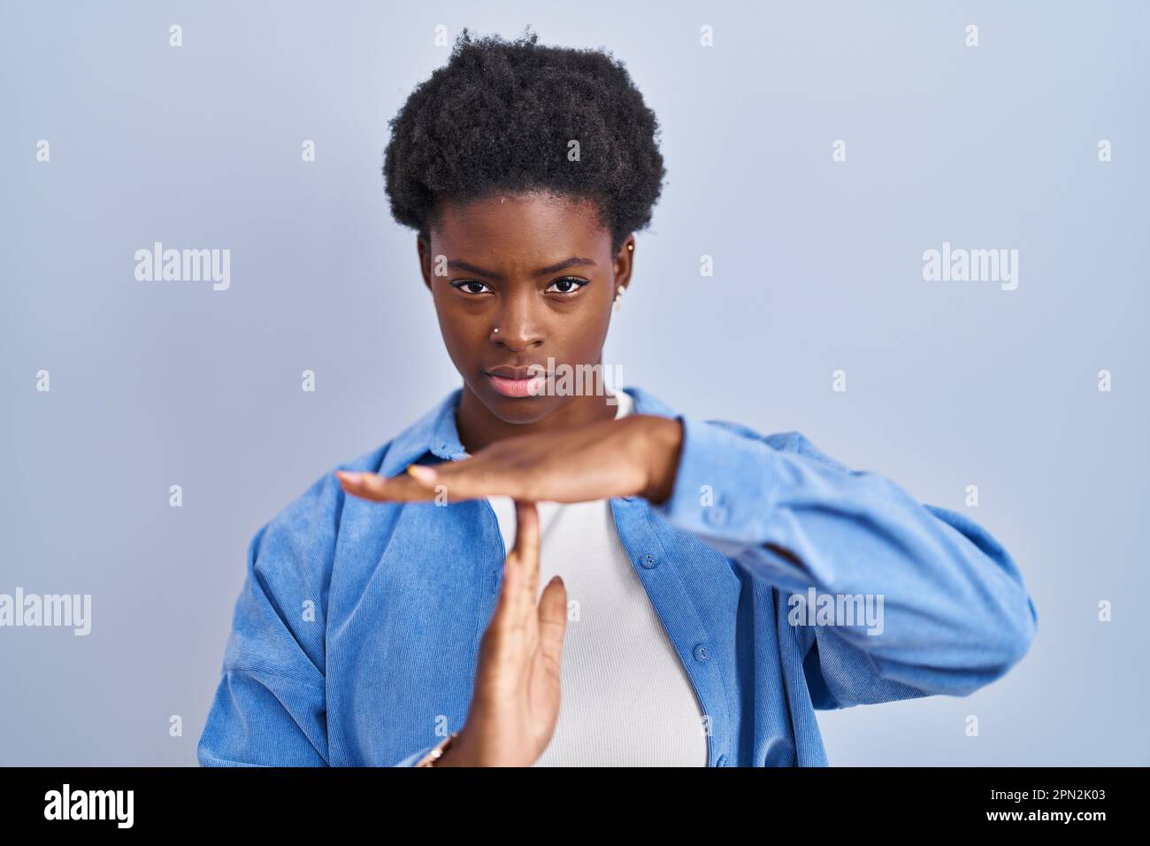 African american woman standing over blue background doing time out ...