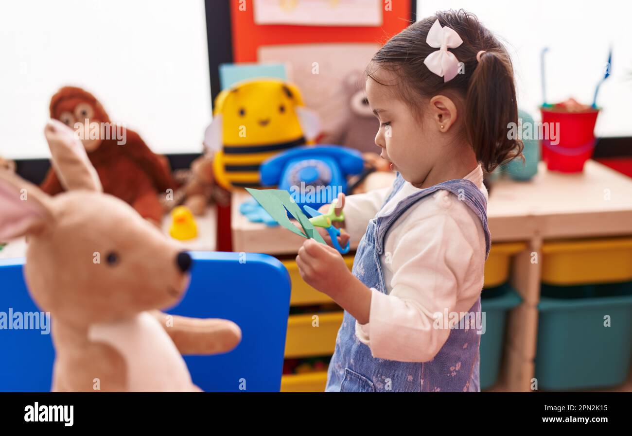 Adorable hispanic girl student cutting paper at kindergarten Stock ...