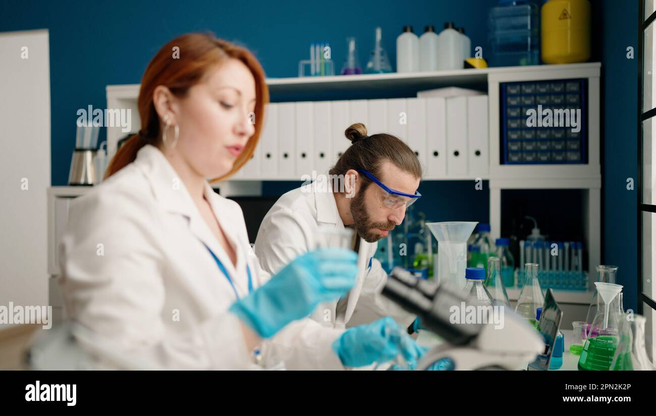 Man and woman wearing sciencist uniform using microscope at laboratory ...