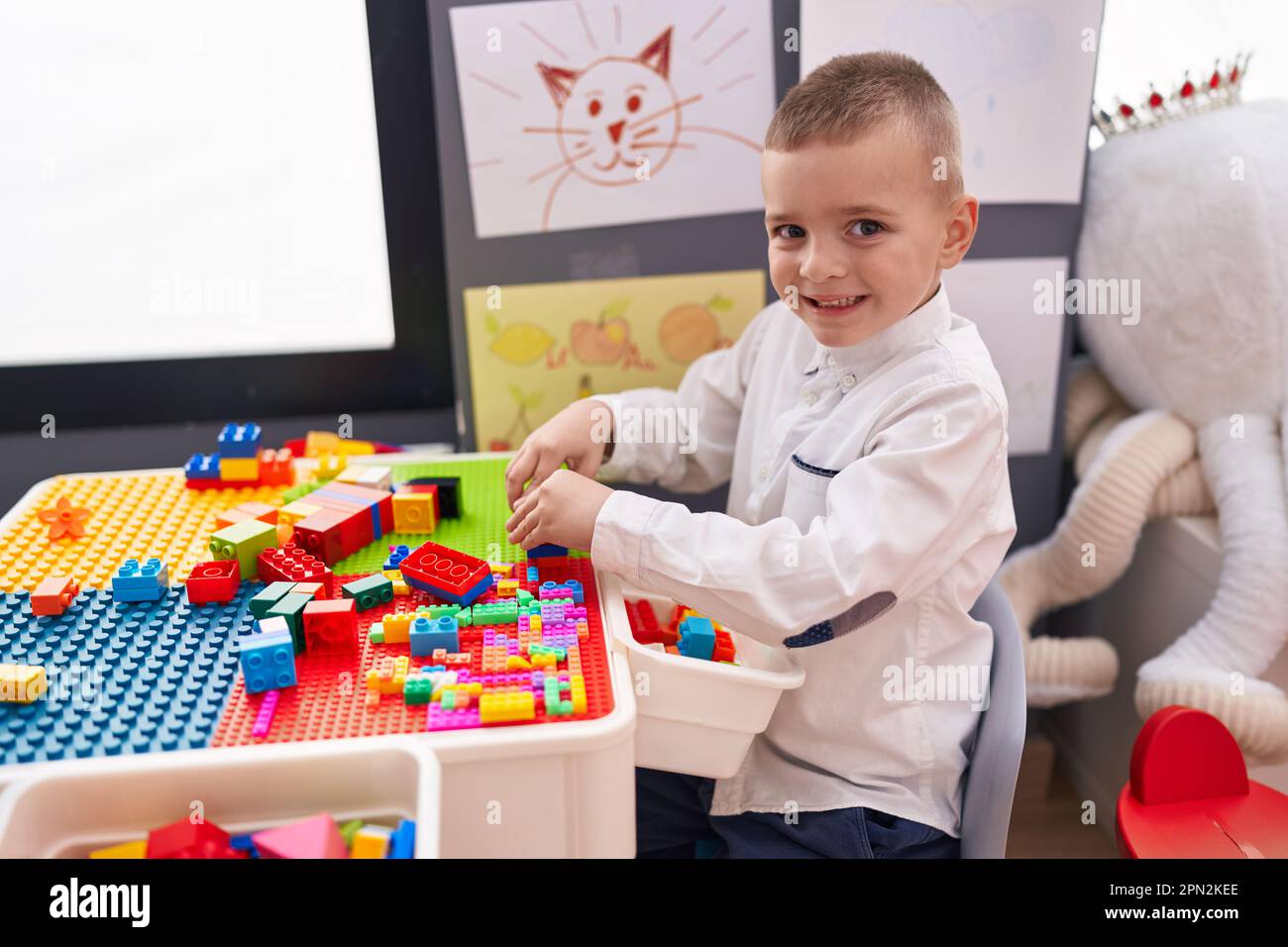 Adorable caucasian boy playing with construction blocks sitting on ...