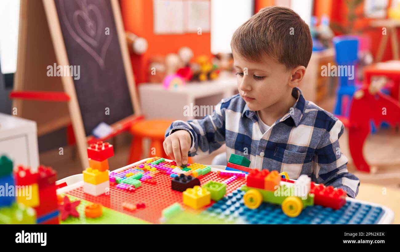 Adorable caucasian boy playing with construction blocks sitting on ...