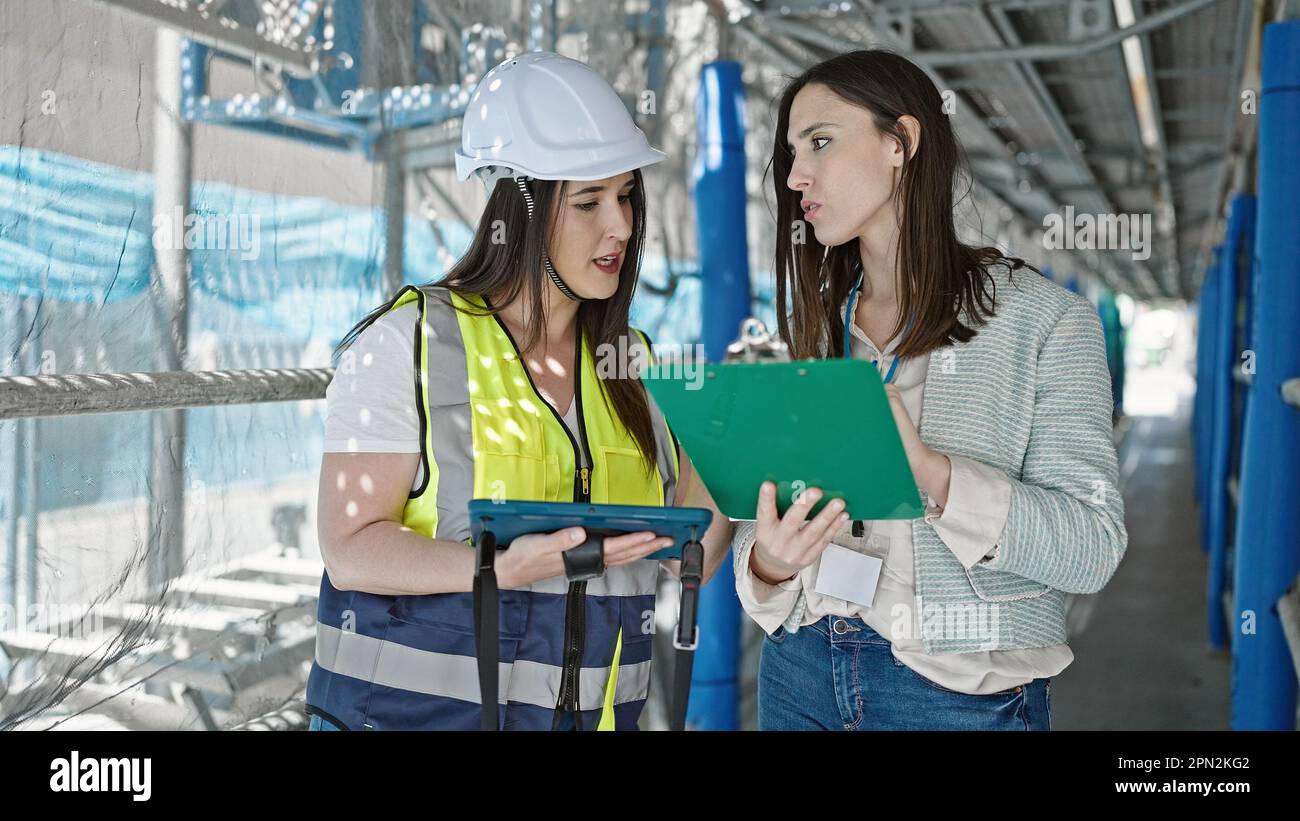 Two women architect and worker using touchpad and clipboard working at ...