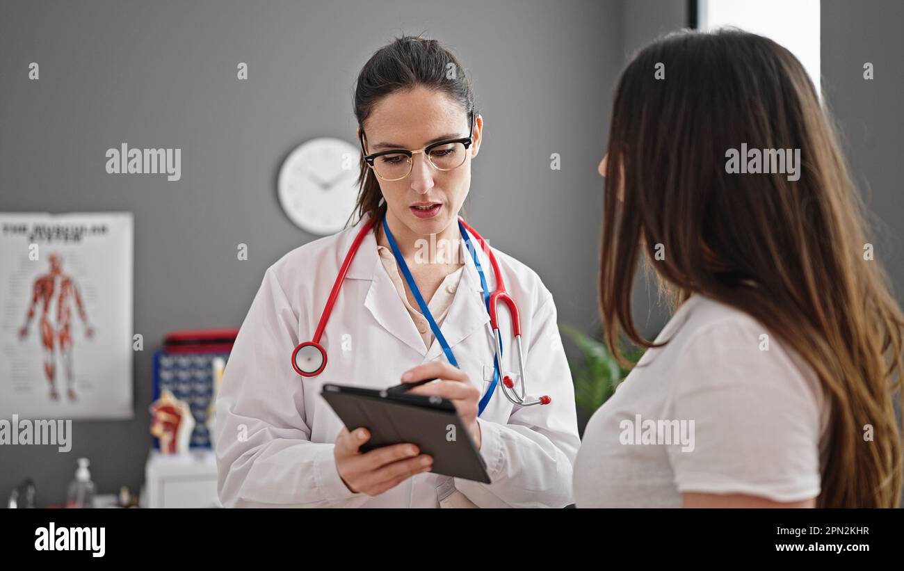 Two women doctor and patient using touchpad having consultation at ...