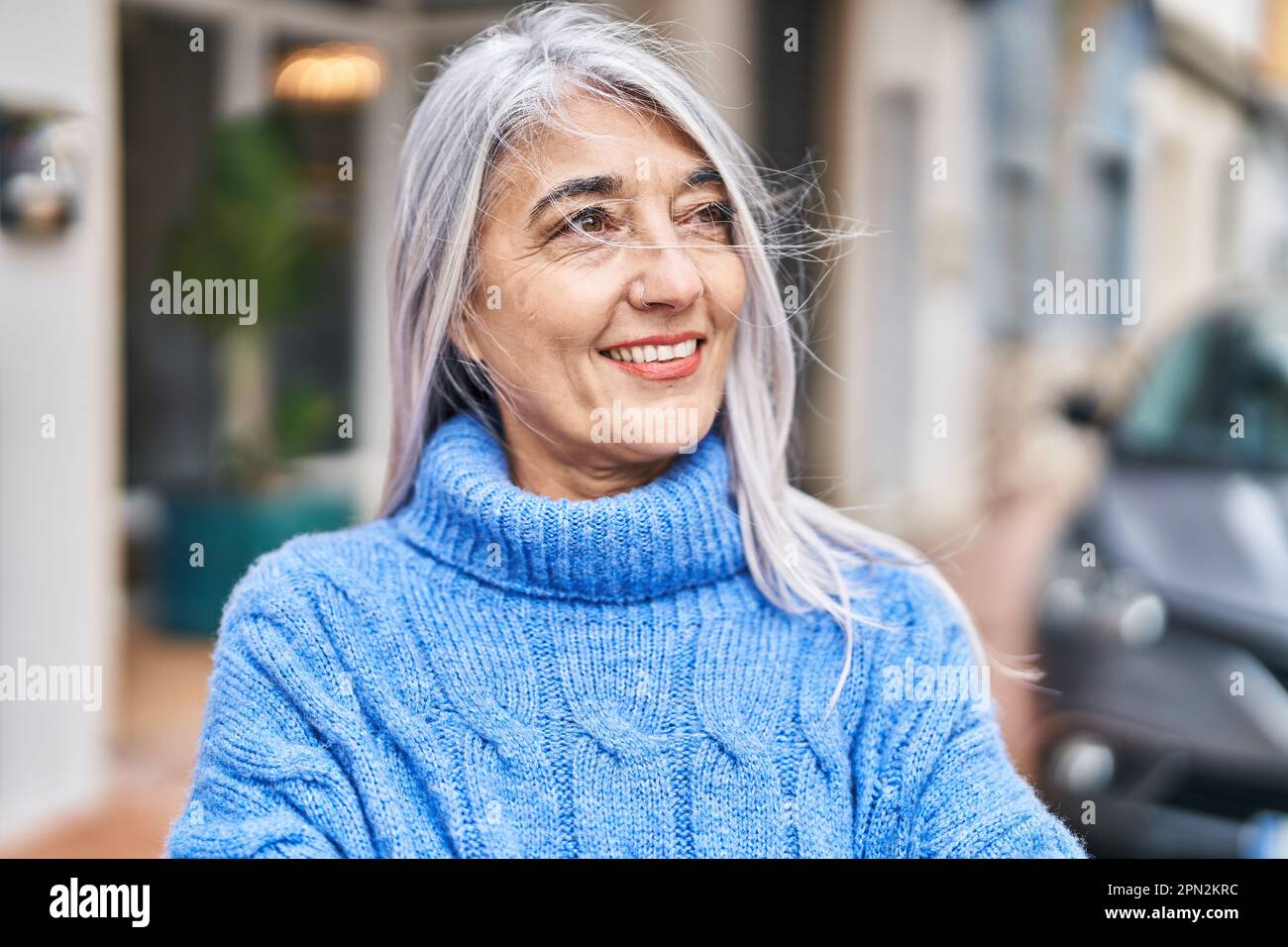 Middle age grey-haired woman smiling confident looking to the side at ...