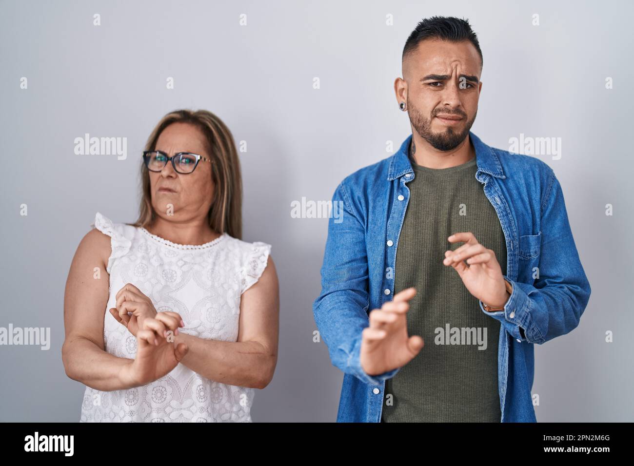 Hispanic mother and son standing together disgusted expression ...