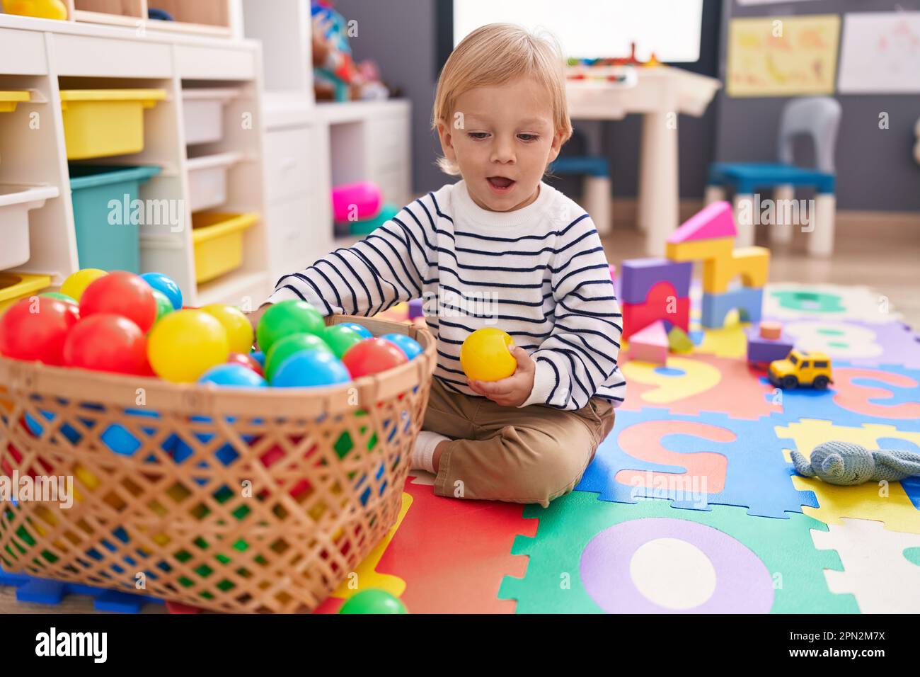 Adorable caucasian boy playing with balls sitting on floor at ...