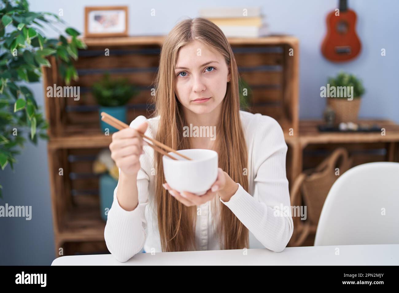 Young caucasian woman eating asian food using chopsticks depressed and ...