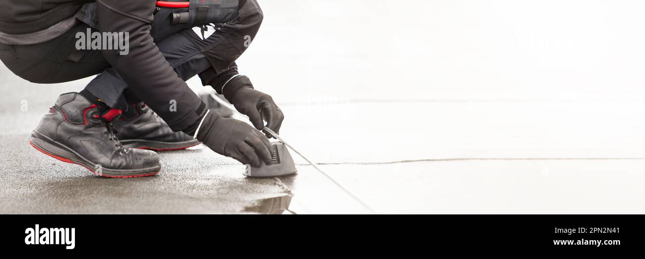 Ground wire. A worker lays a ground cable on the roof of a building ...