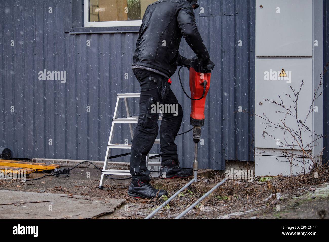 A worker installs a ground rod to ground a building. A worker in work ...