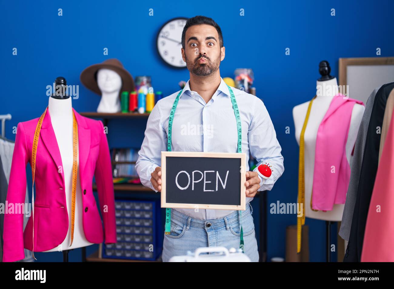 Hispanic man with beard working as dressmaker at atelier puffing cheeks ...