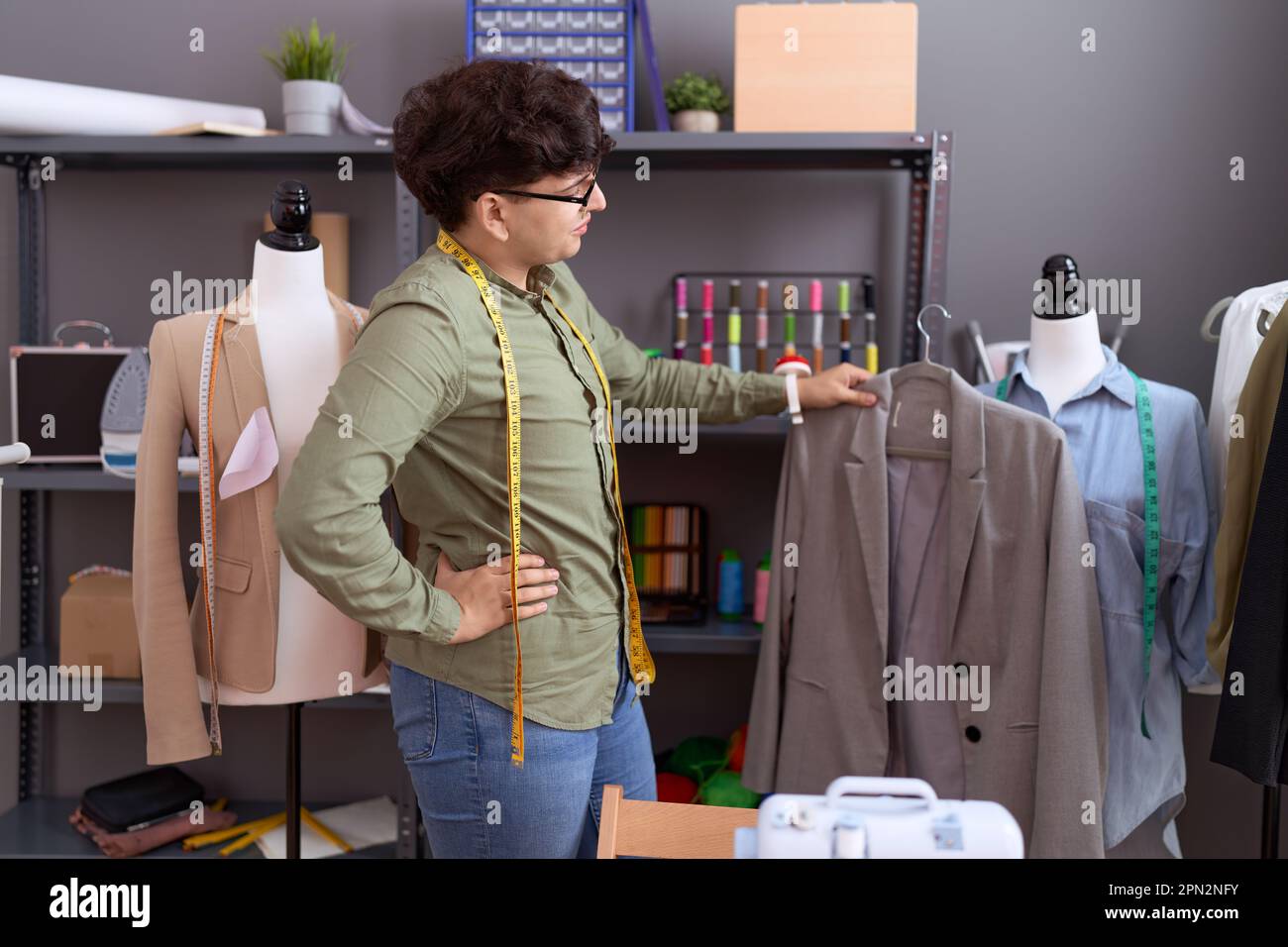 Non binary man tailor holding jacket at atelier Stock Photo - Alamy