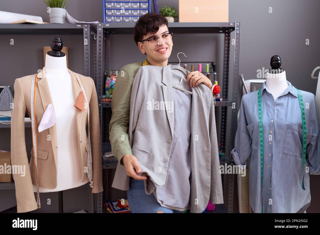 Non binary man tailor smiling confident holding jacket at atelier Stock ...
