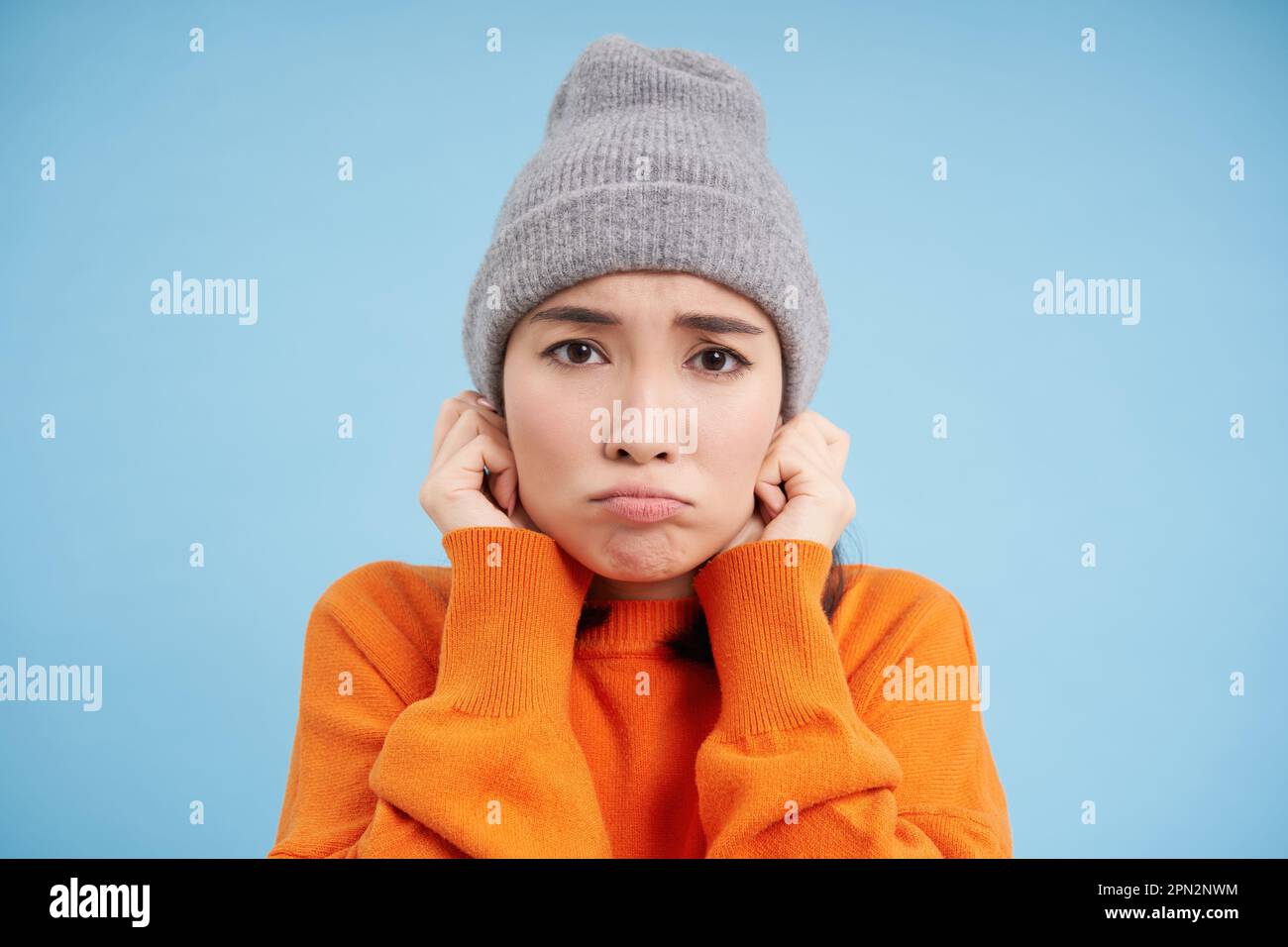 Close up portrait of korean girl feels cold, shakes and freezes, puts ...