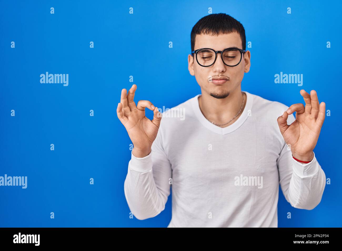 Young arab man wearing casual white shirt and glasses relax and smiling ...