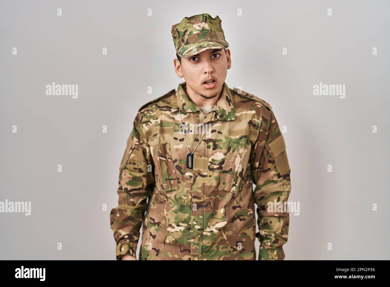 Young arab man wearing camouflage army uniform in shock face, looking ...