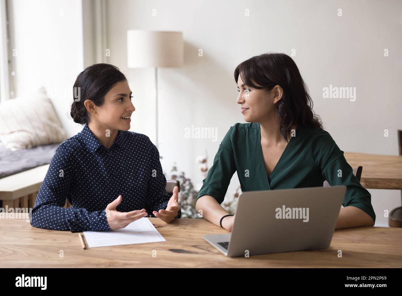 Two women coworkers working together, cooperate, engaged in teamwork ...