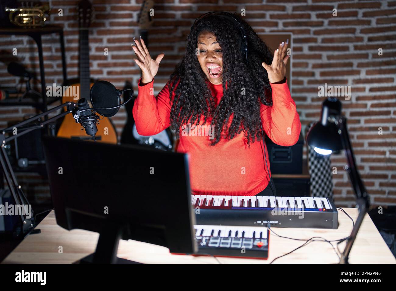 Plus size hispanic woman playing piano at music studio celebrating ...