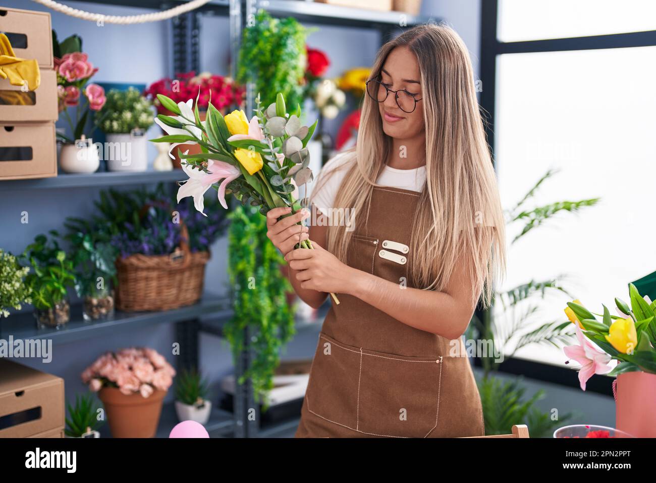Young beautiful hispanic woman florist holding bouquet of flowers at ...