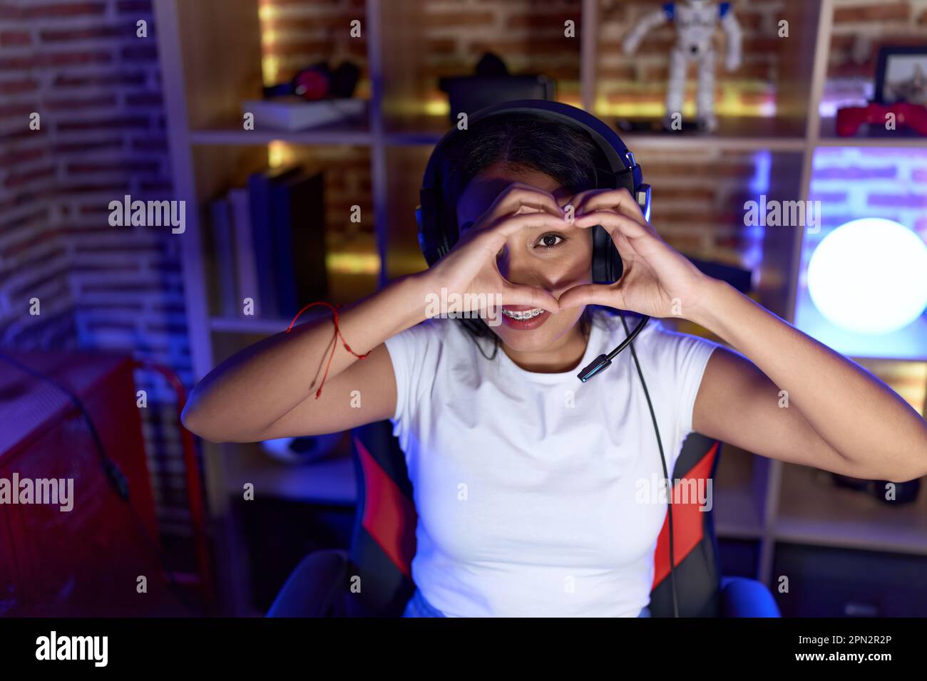Young arab woman streamer smiling confident doing heart symbol with ...