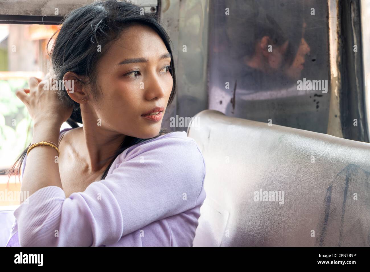 A young woman sits in a old bus and looks back through the rear window ...