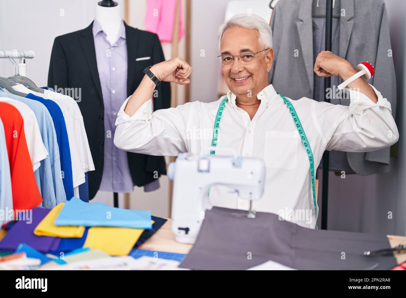 Middle age man with grey hair dressmaker using sewing machine showing ...